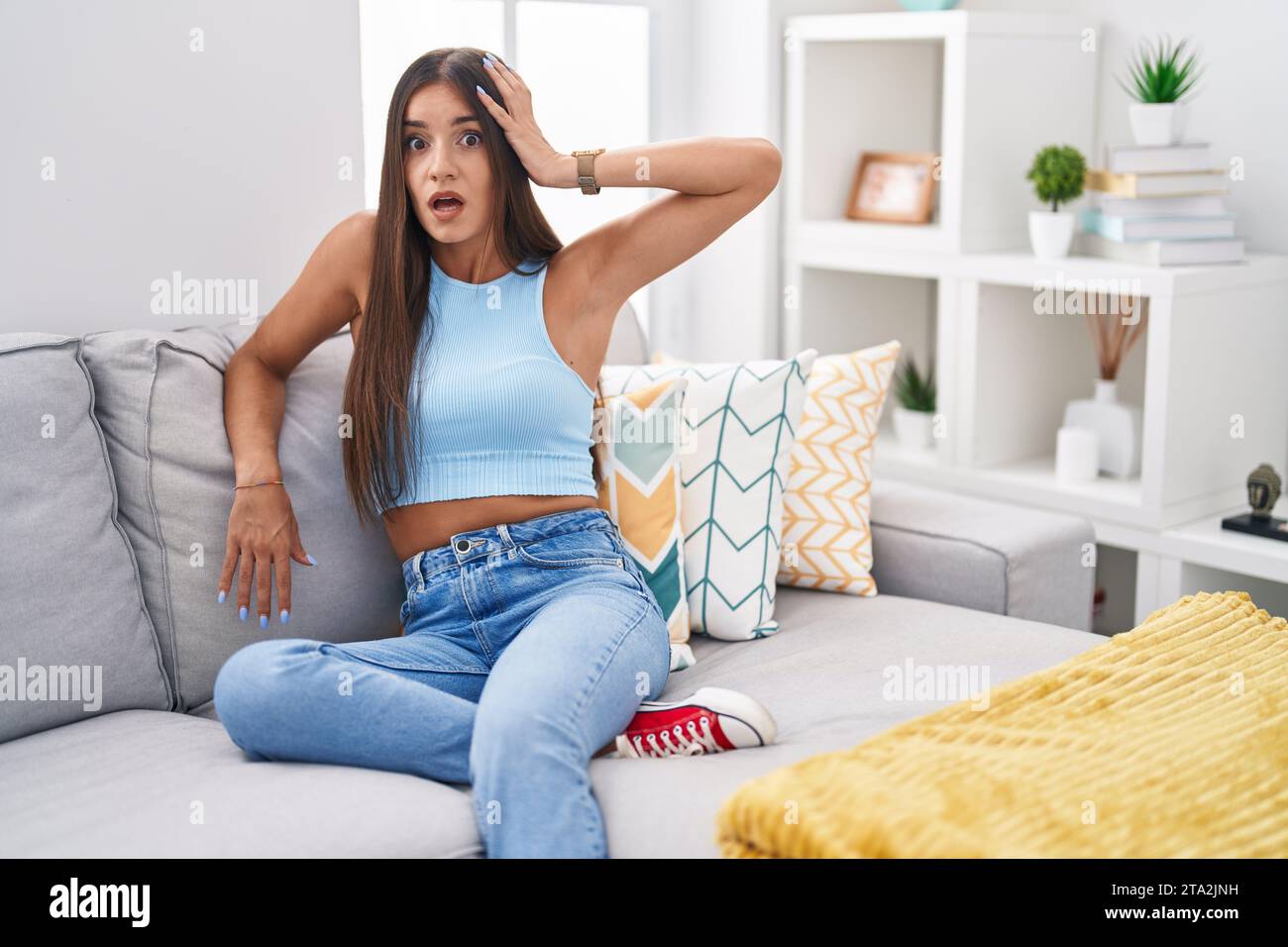 Young brunette woman sitting on the sofa at home crazy and scared with ...