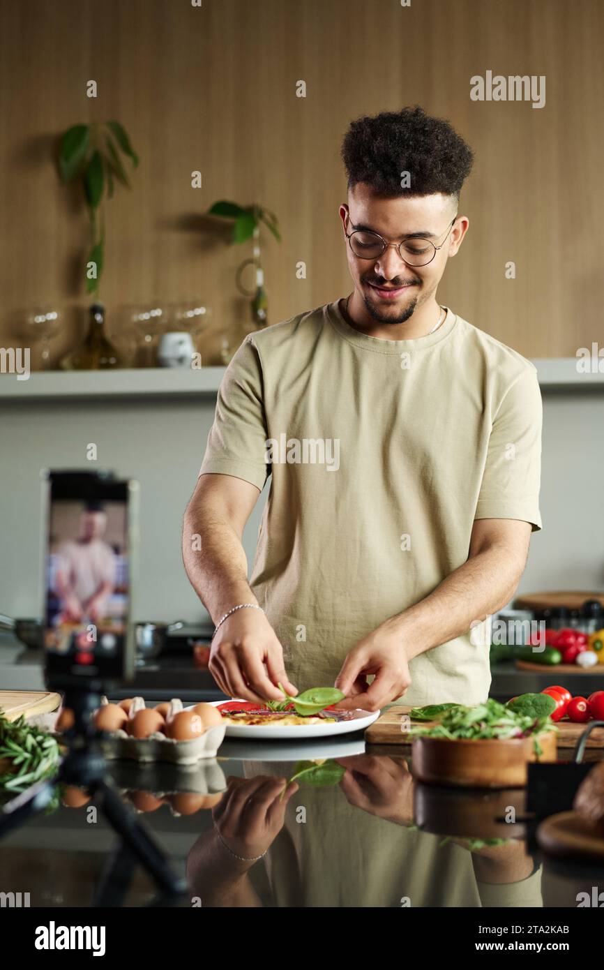 Medium shot of young middle eastern chef putting leaf of spinach on top ...