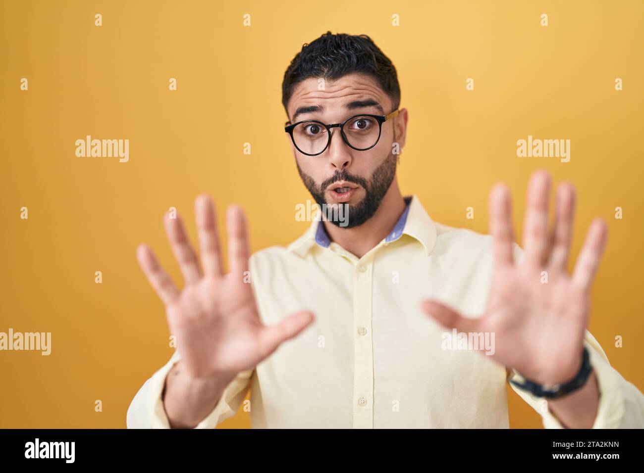 Hispanic young man wearing business clothes and glasses afraid and ...