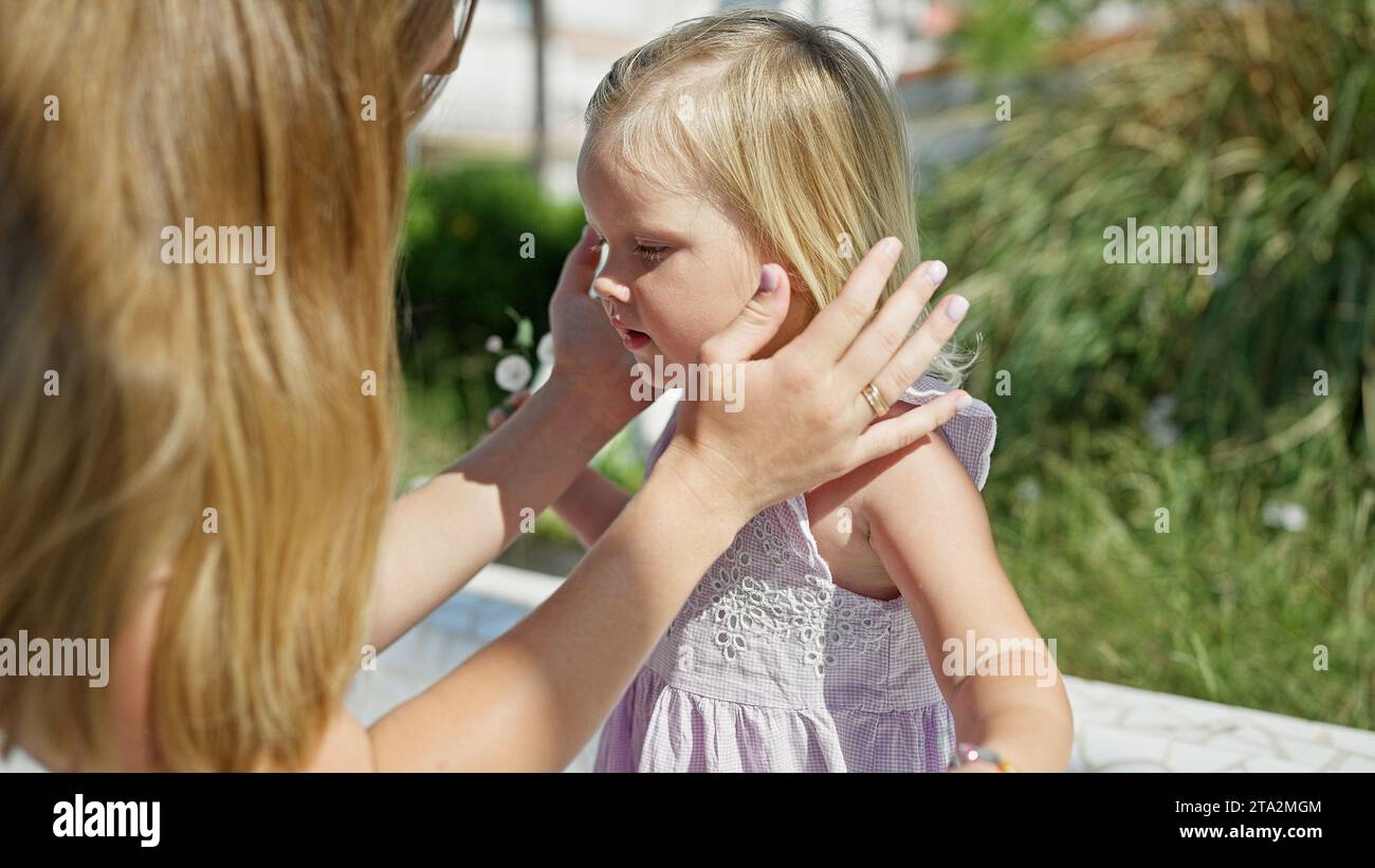 Mother and daughter sitting together on park bench, serious ...