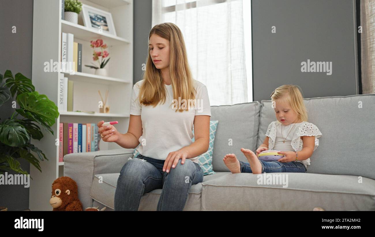 Cozy at home, a caring caucasian mother and her little girl resting on ...