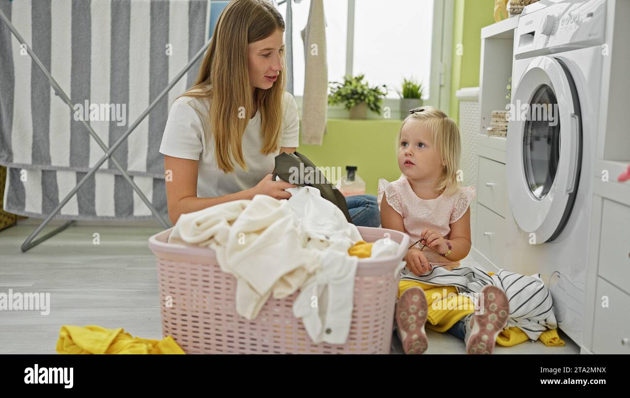 Caucasian mother and daughter bonding over laundry chores, sitting on ...