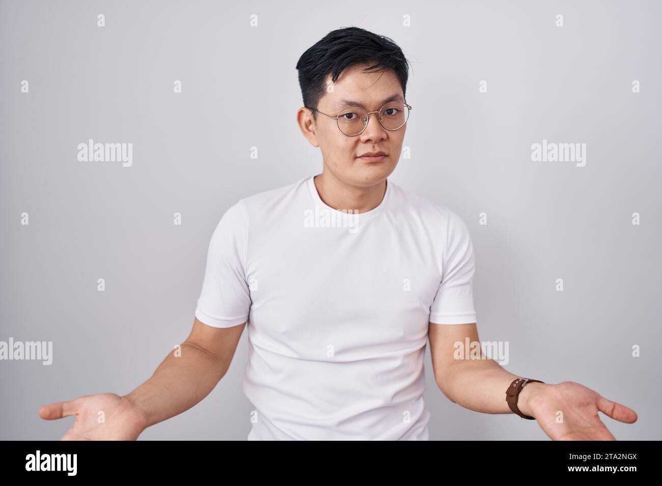 Young asian man standing over white background clueless and confused ...