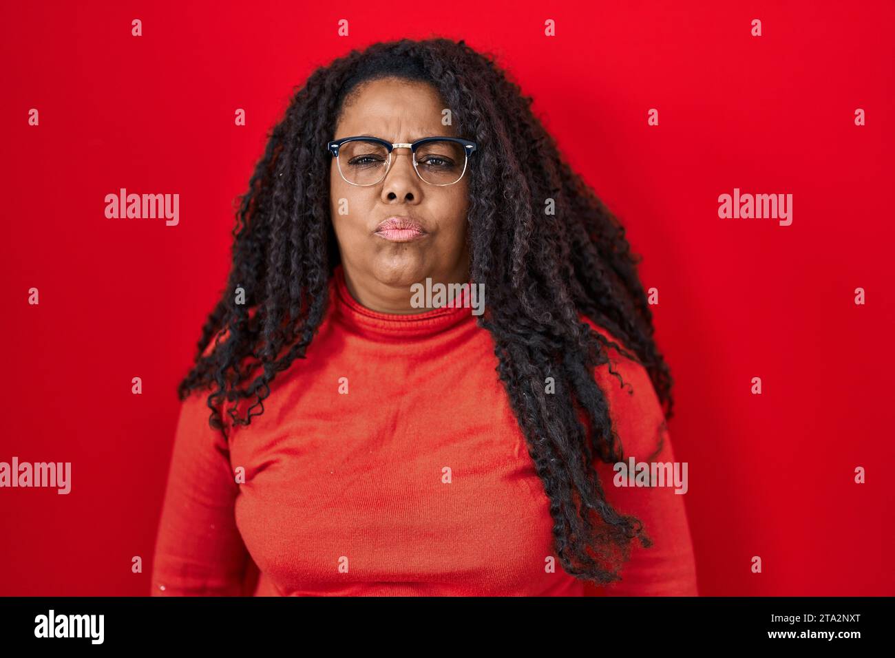 Plus size hispanic woman standing over red background depressed and ...