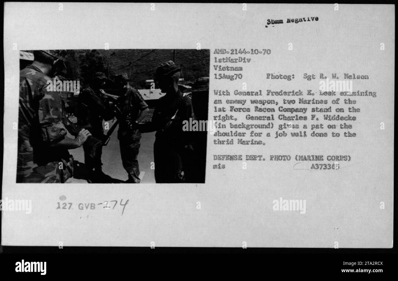 Caption: General Frederick E. Leek examines an enemy weapon, while two ...