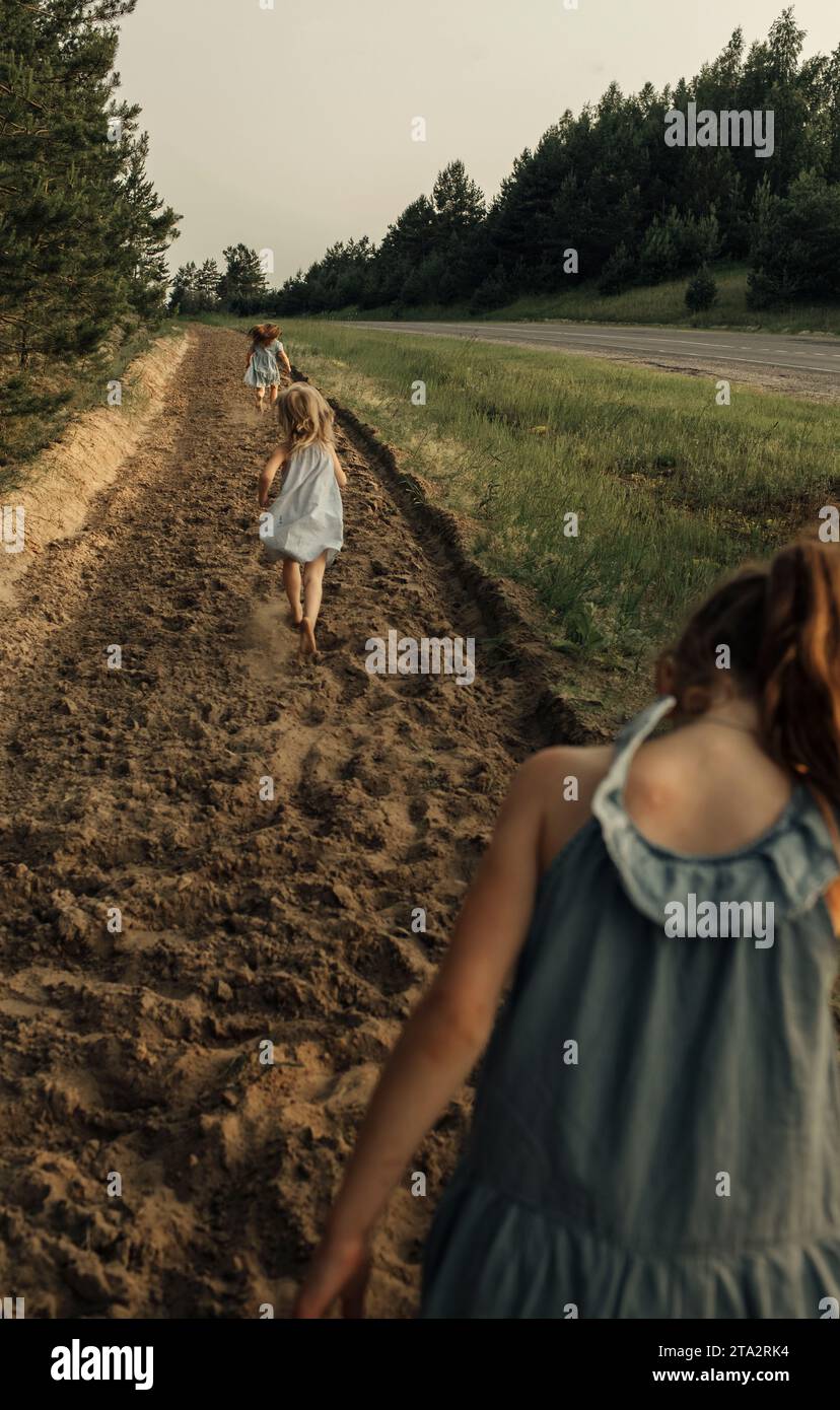 Little girls - sisters play, running along a path along the forest ...