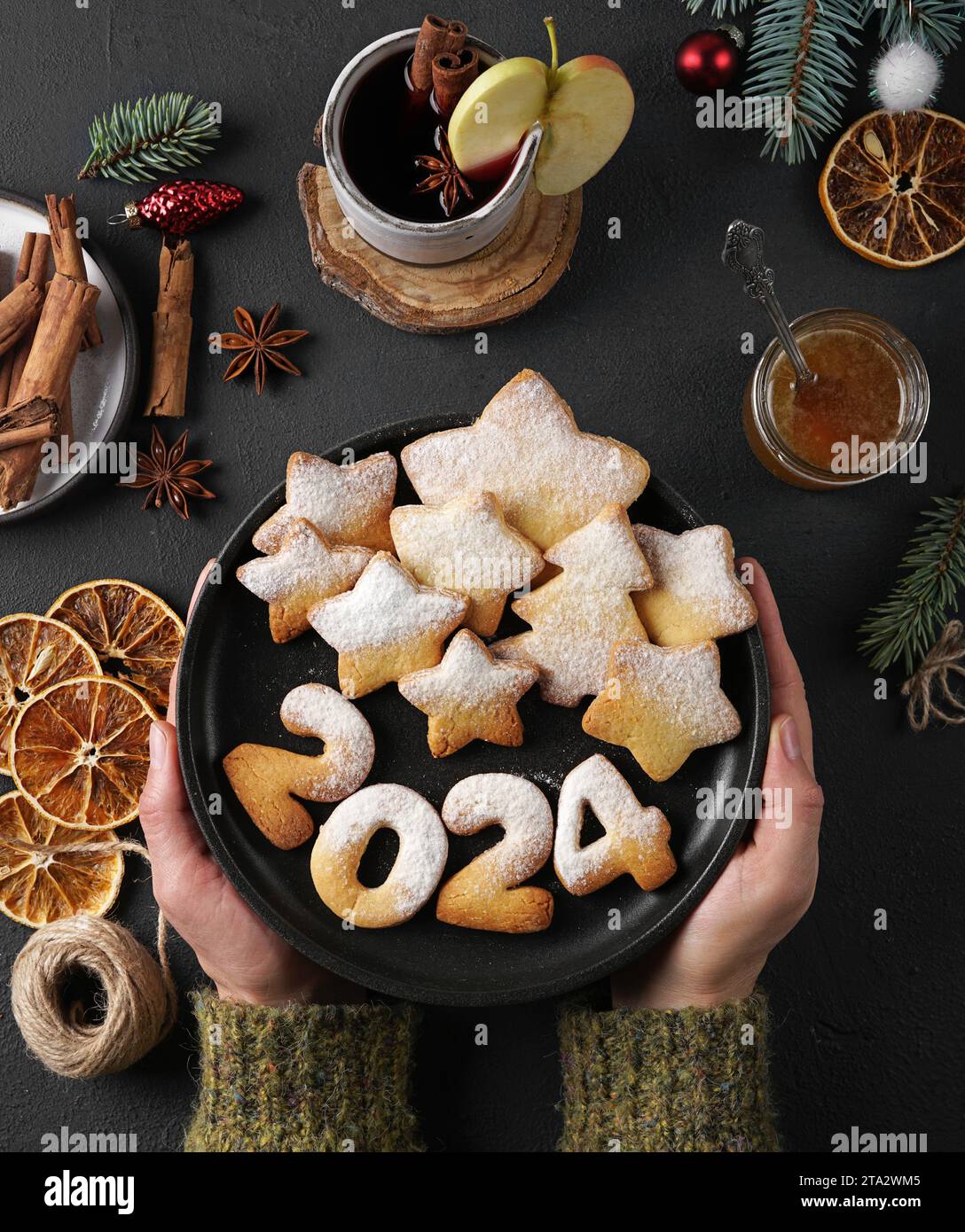 Cookies in the form of numbers 2024 and stars on the dark plate holding ...