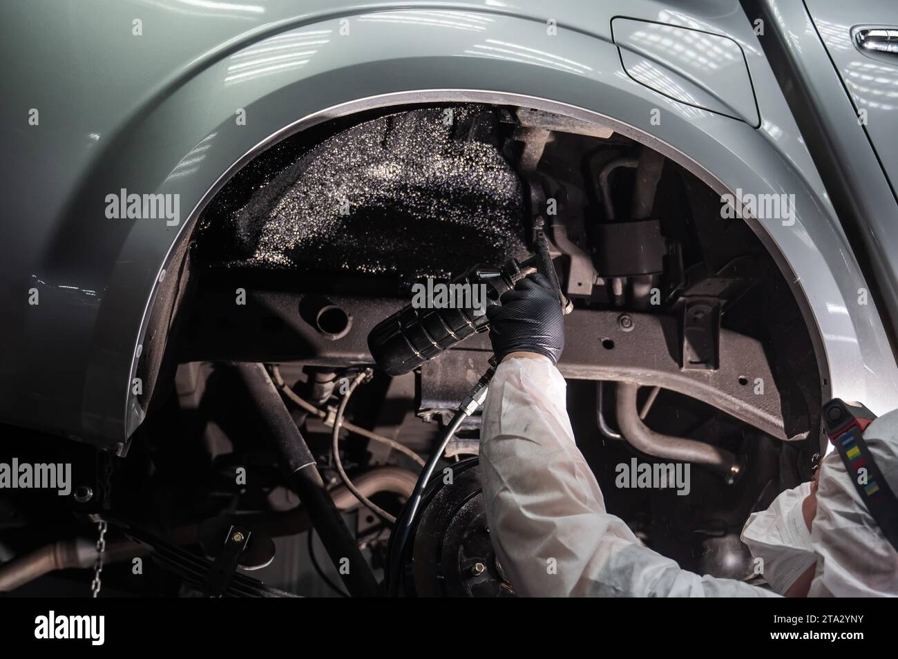 The master sprays an anti-corrosion compound on the bottom of the car ...