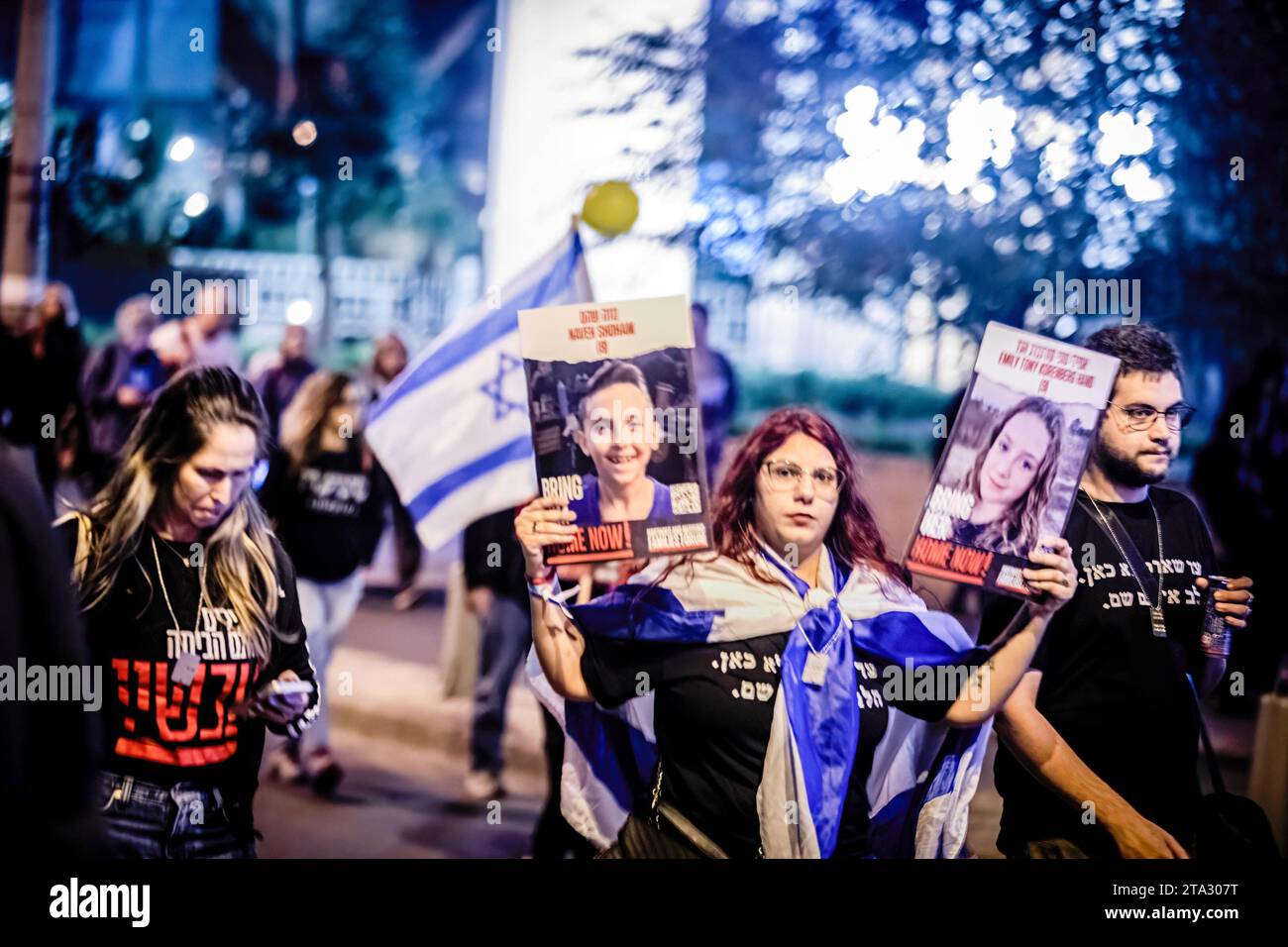 A woman walks through the street while holding photos of Naveh Shoham ...