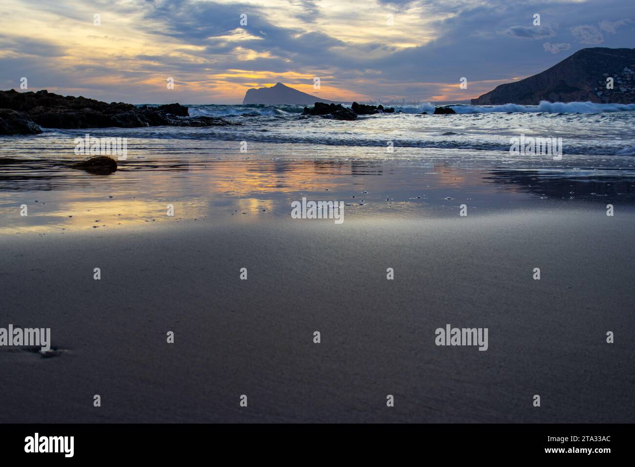 Sunset on the beach overlooking the waves, mountains and wet sand on ...
