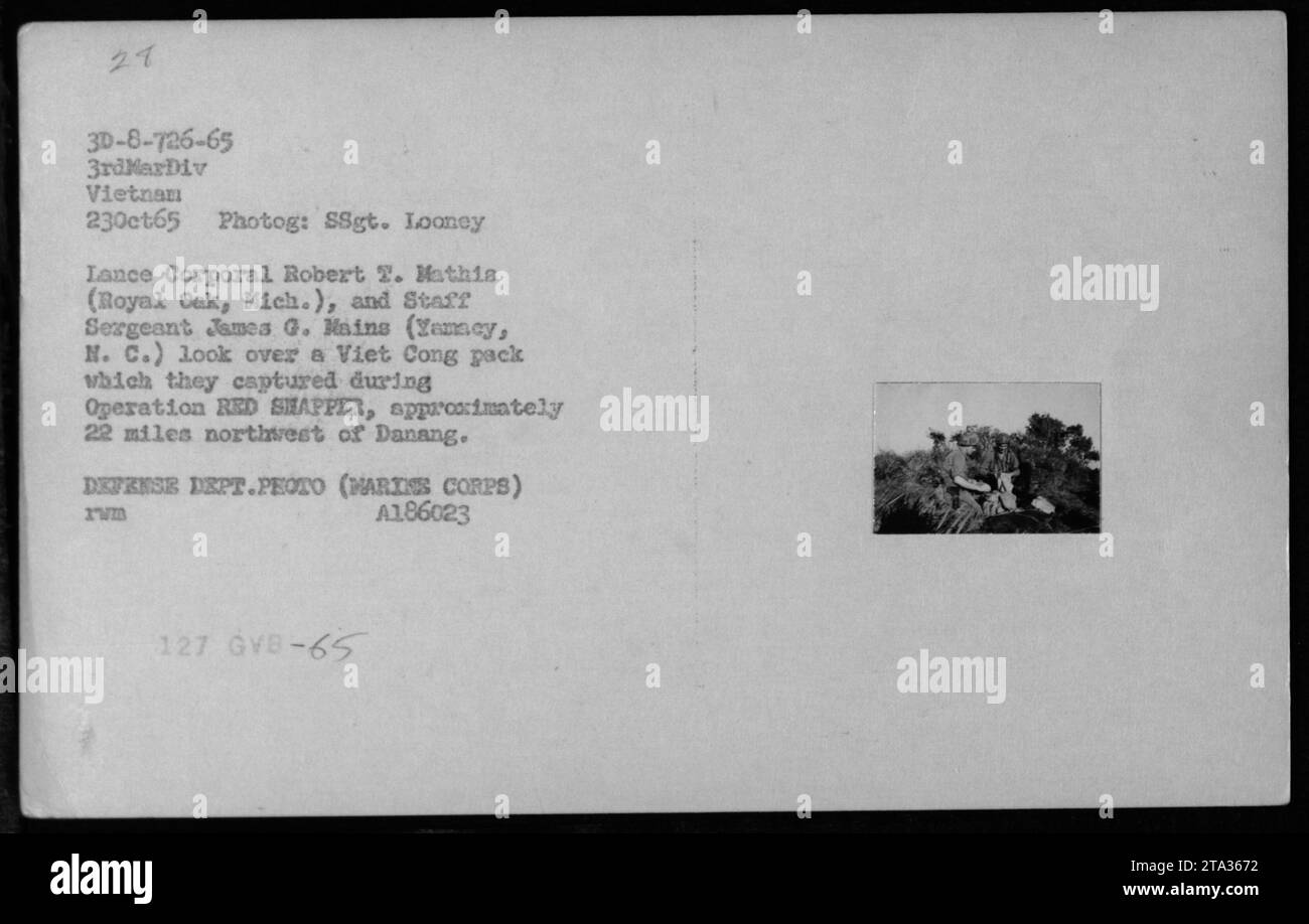 Marine Corps Lance Corporal Robert T. Mathis and Staff Sergeant James G. Mains inspect a pack of ...