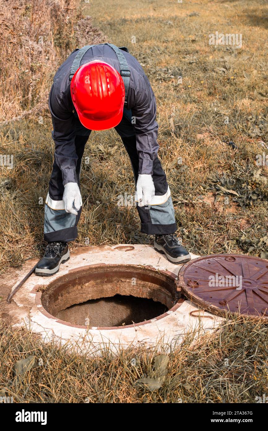 The plumber opened the well hatch and leaned over it. Maintenance of ...