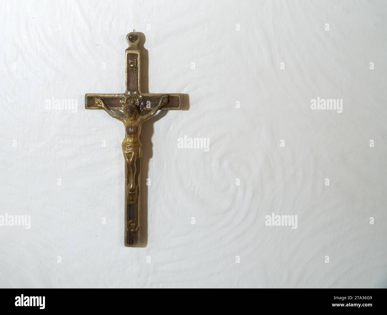 Small brass Christian cross on a wall Stock Photo - Alamy