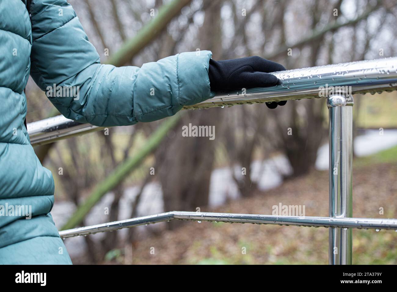 woman holding on to metal railing while climbing stairs in rainy ...