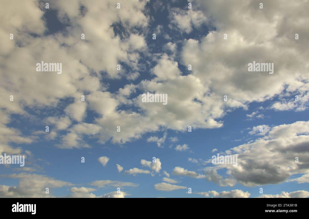 A blue cloudy sky with many small clouds blocking the sun Stock Photo ...