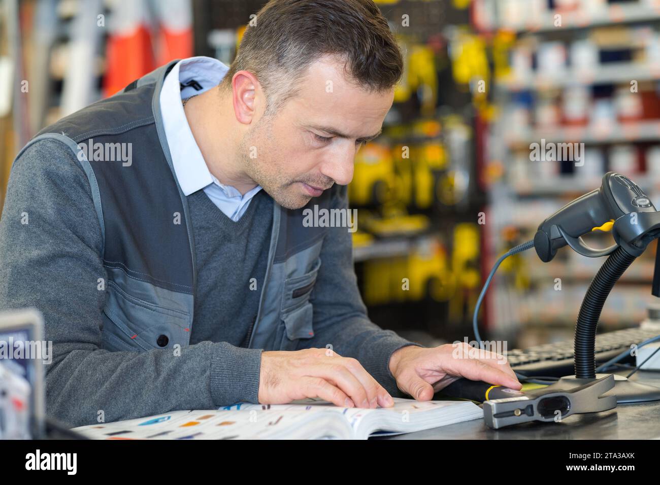 worker in hardware store looking up reference in catalogue Stock Photo ...