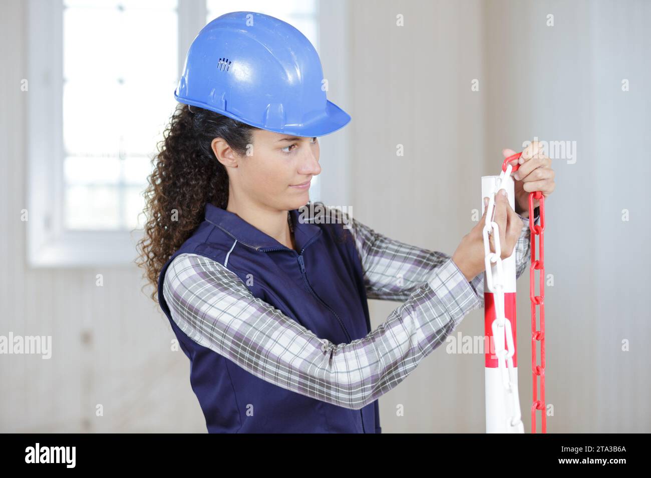 female builder putting up a safety cordon around work site Stock Photo ...