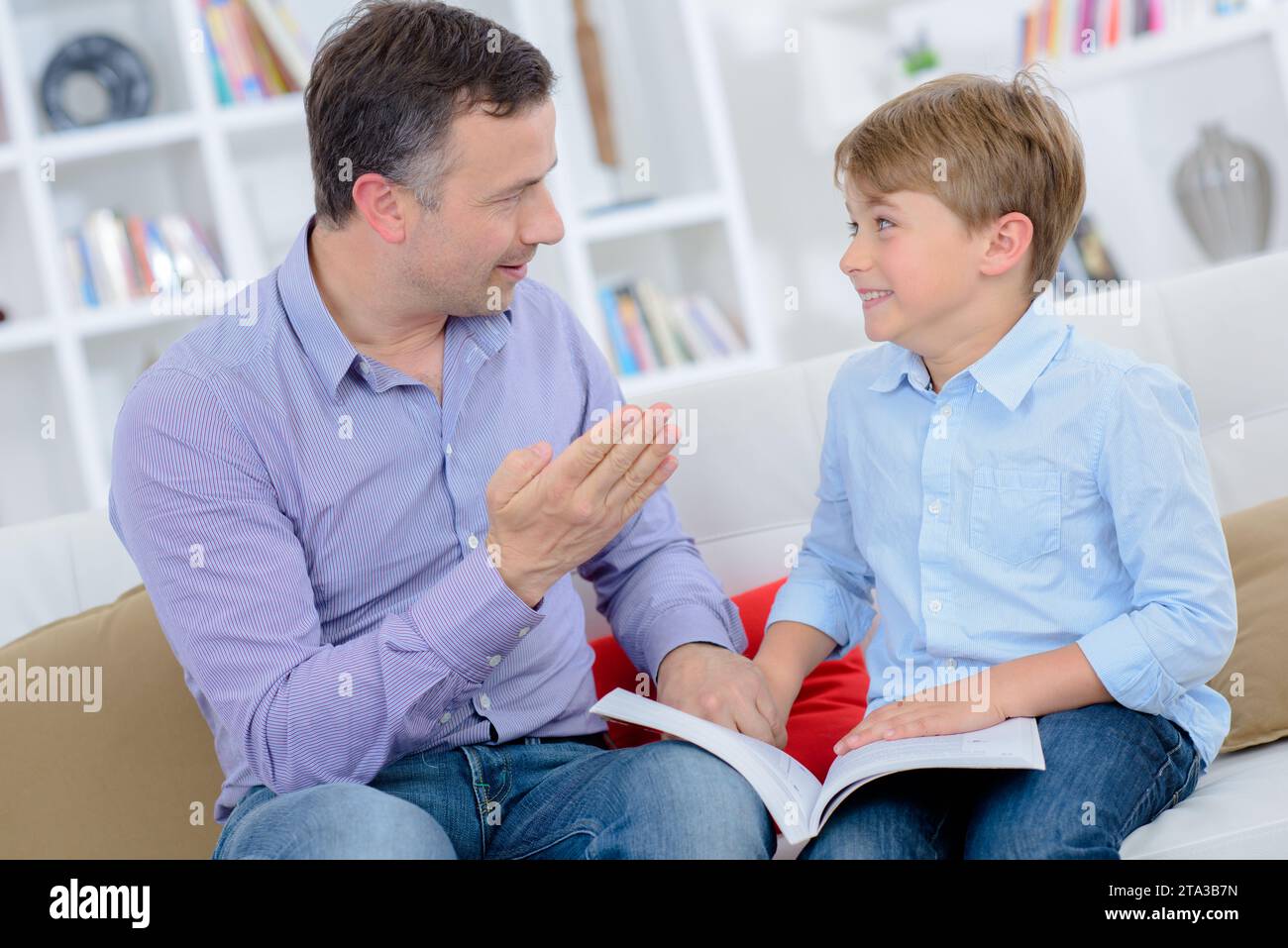 Man and child reading book and talking Stock Photo - Alamy