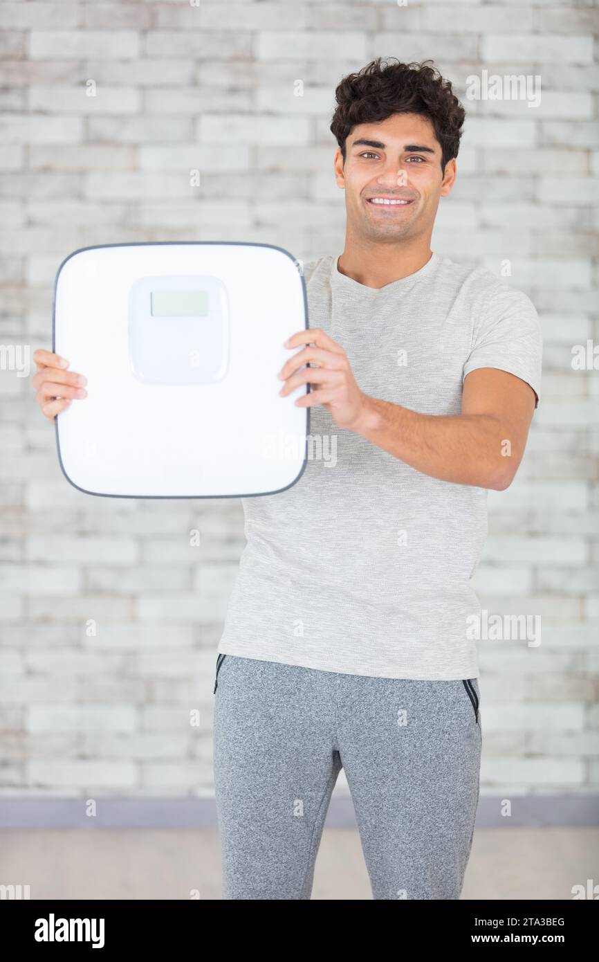 portrait of a happy excited fitness man holding weight scales Stock ...