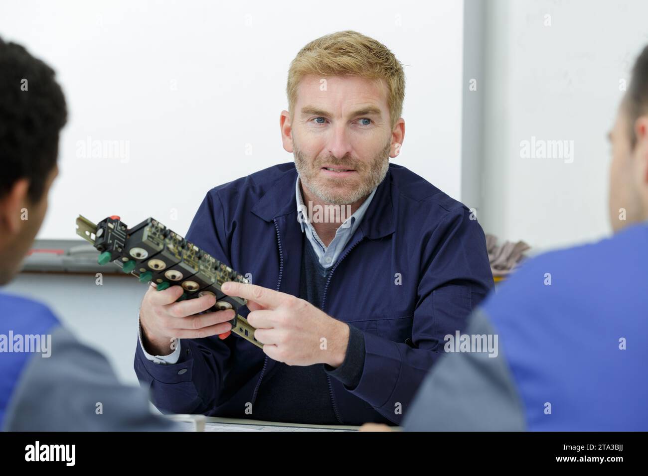 mechanic teacher showing a piece of mechanical parts to apprentice ...