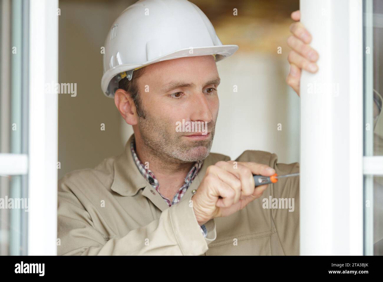 repairman fixing window with screwdriver Stock Photo - Alamy