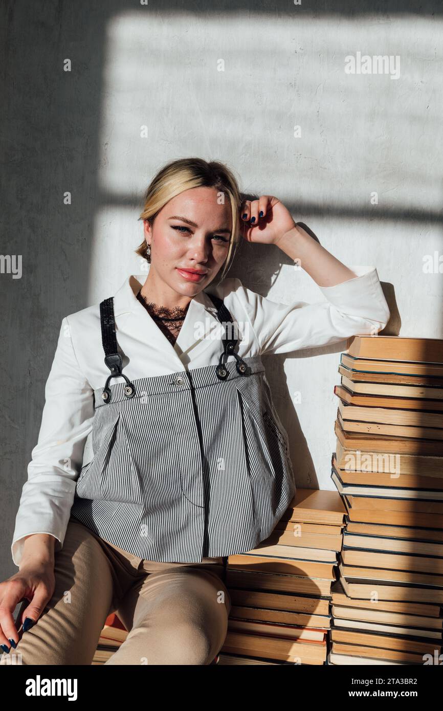Beautiful smart woman sitting on books loves to read Stock Photo - Alamy