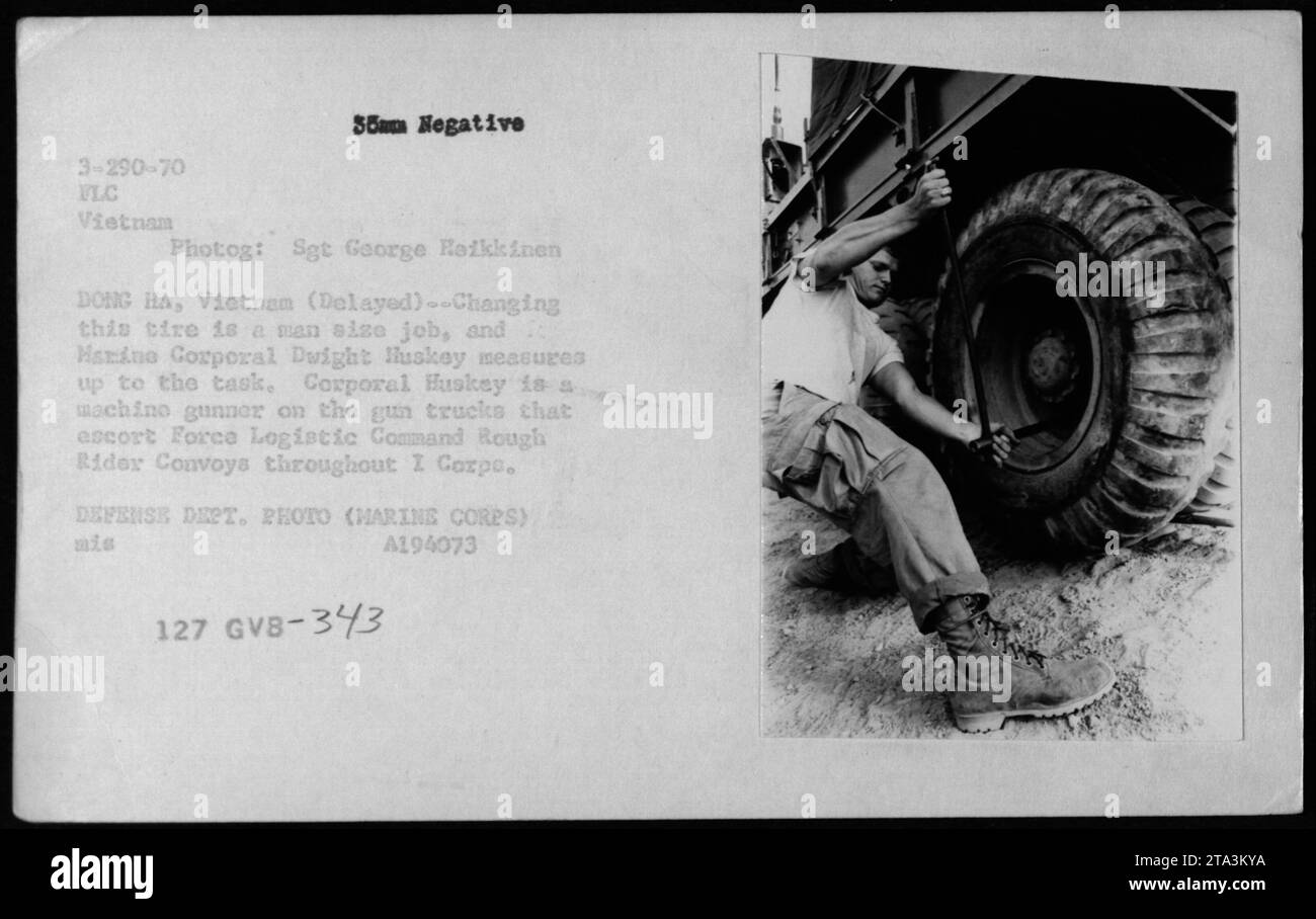 A Marine Corps machine gunner, Corporal Dwight Huskey, changes a tire ...