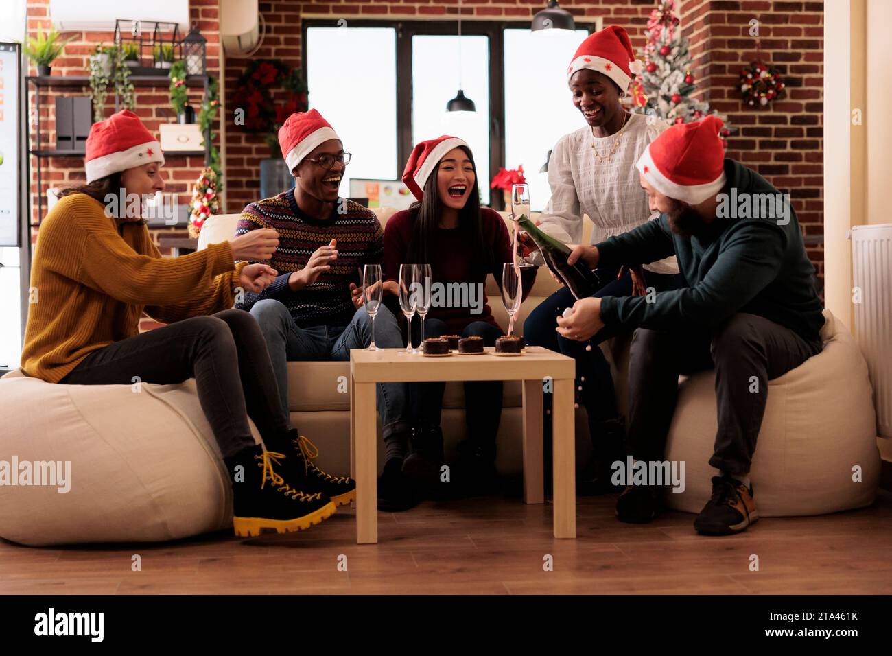 Cheerful coworkers team pouring sparkling wine into glasses at ...