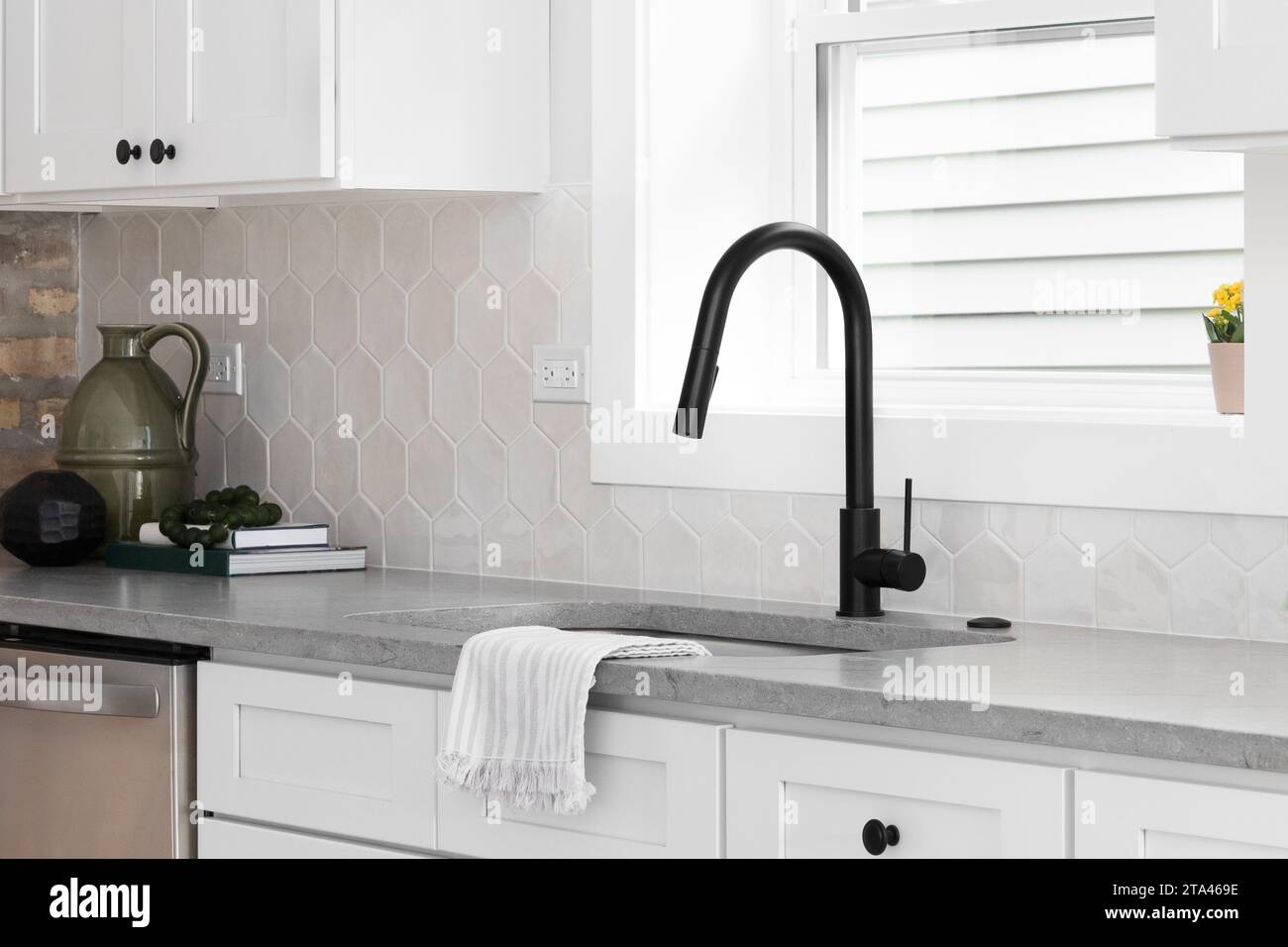 A beautiful kitchen sink detail with white cabinets, marble countertops ...