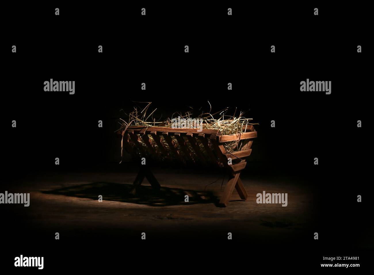 Manger with hay on wooden table against dark background Stock Photo - Alamy