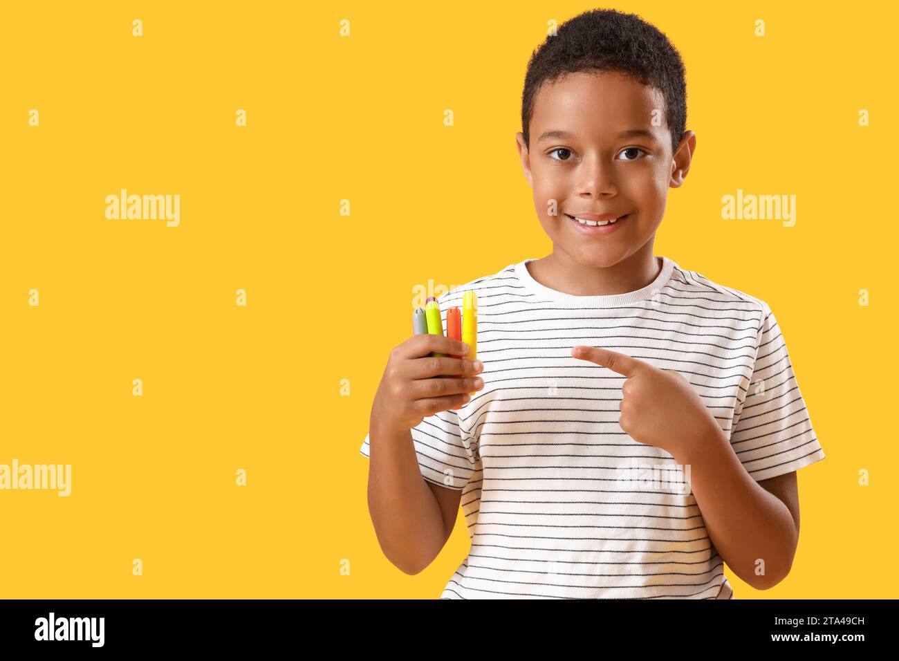 Little African-American boy pointing at felt-tip pens on yellow ...