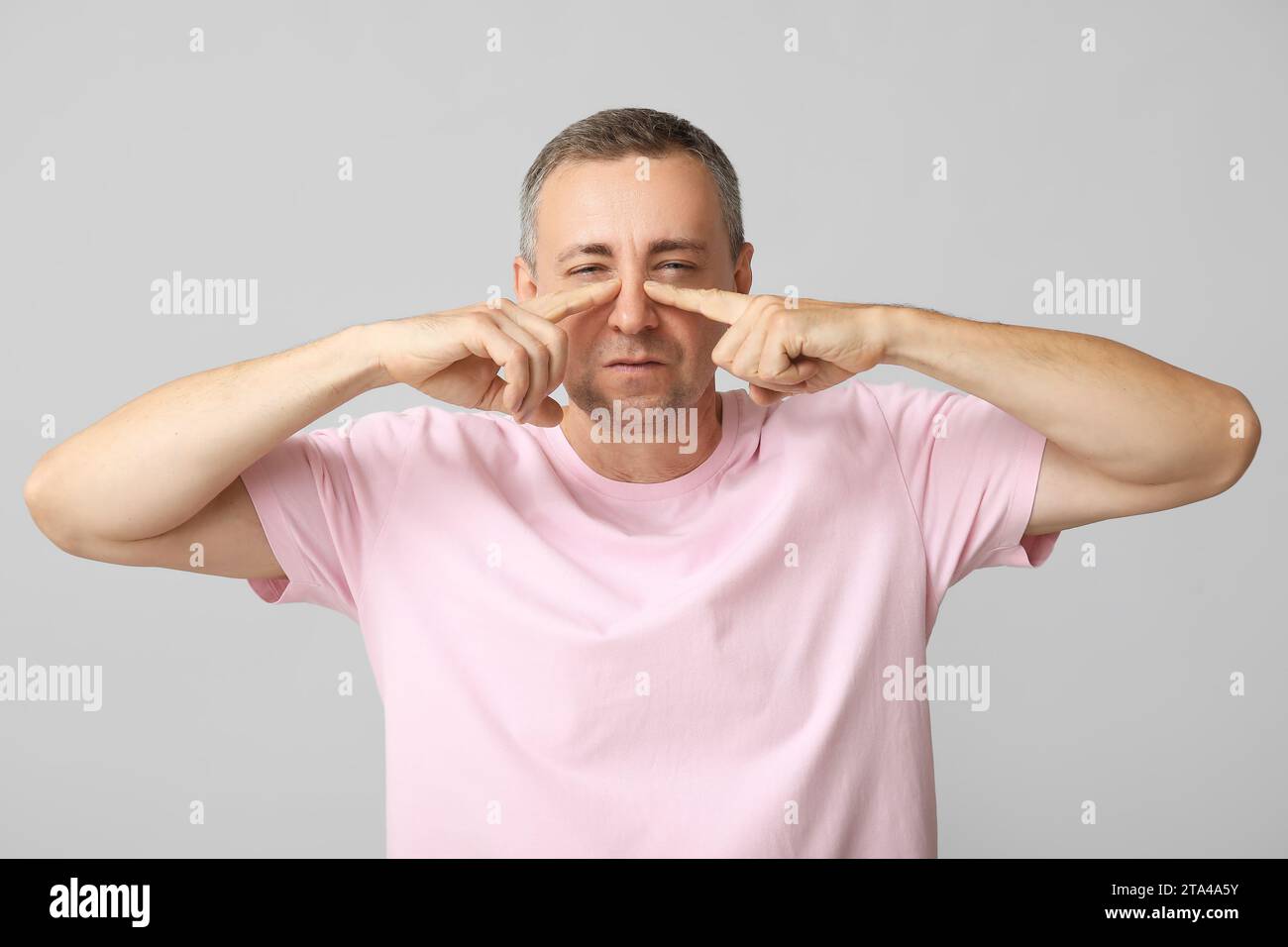 Ill mature man pointing at nose on grey background Stock Photo - Alamy