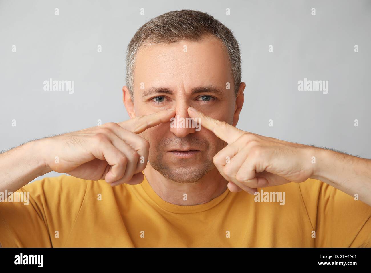 Ill mature man pointing at nose on grey background Stock Photo - Alamy