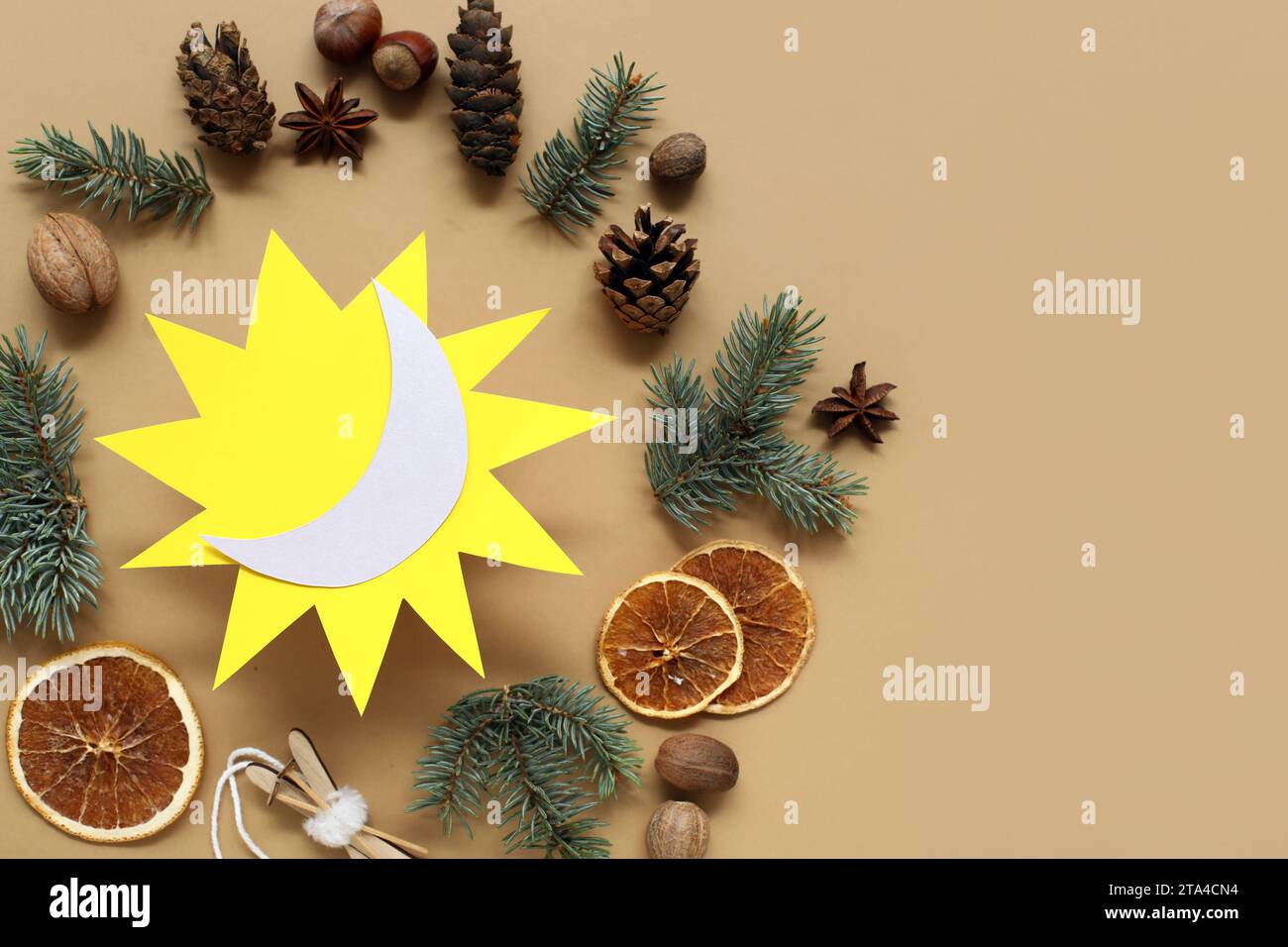 Paper sun with fir branches, dried oranges, cones and nuts on beige ...