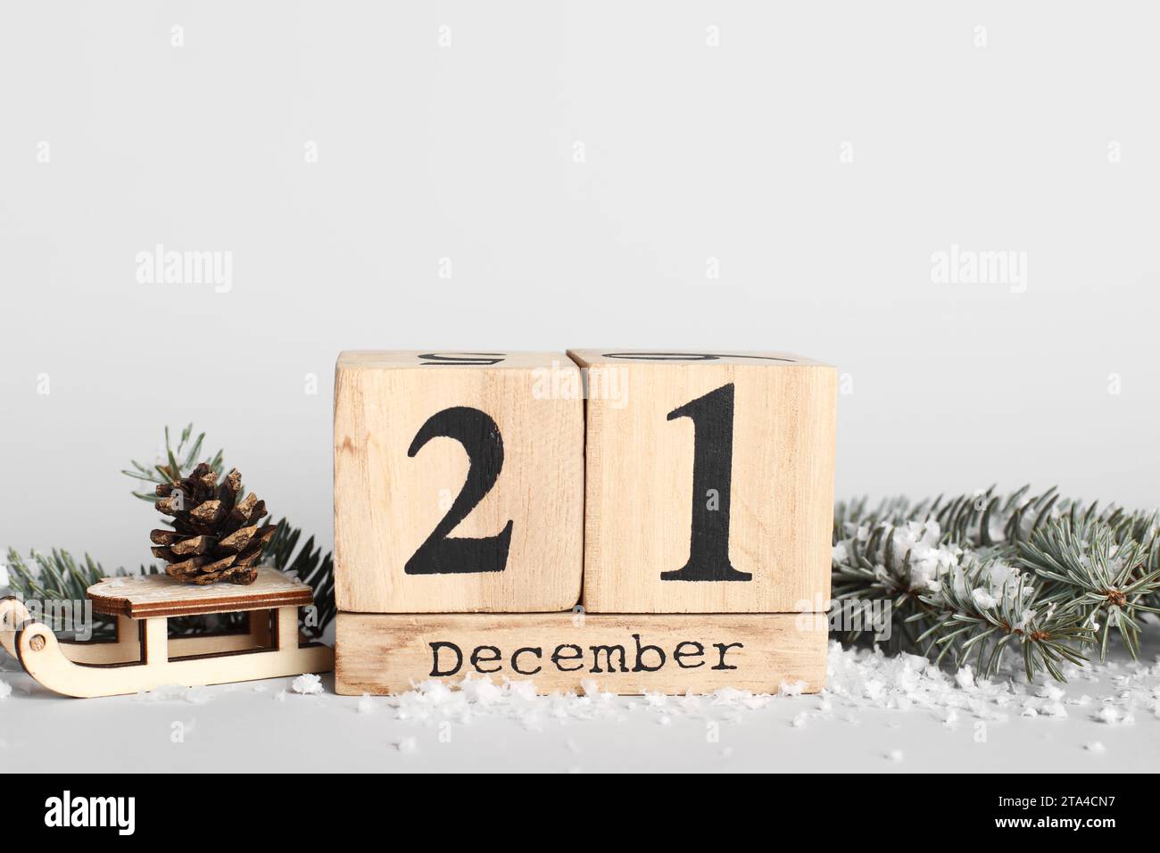 Cube calendar with date of winter solstice, wooden sledge, fir cone ...