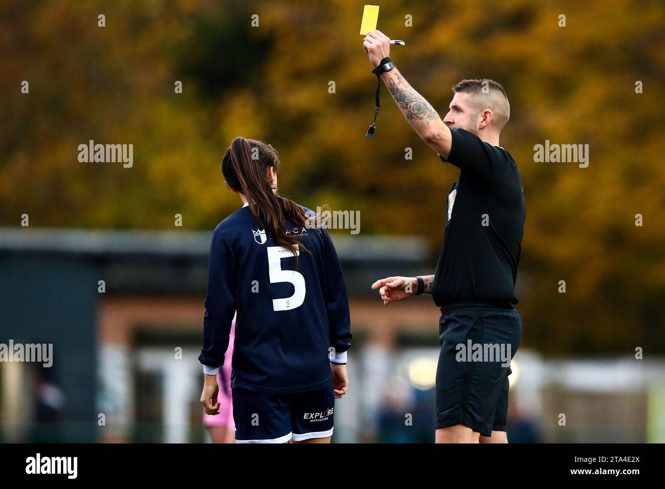 Male referee awards a yellow card to a female football player Stock ...