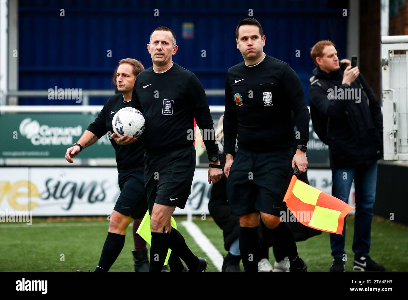 Male referee team walk out onto the pitch with the match ball Stock ...