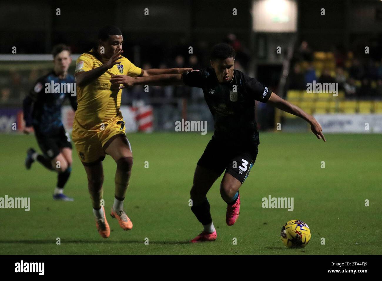 Sutton, UK. 28th Nov, 2023. Rio Adebisi of Crewe Alexandra fends off ...