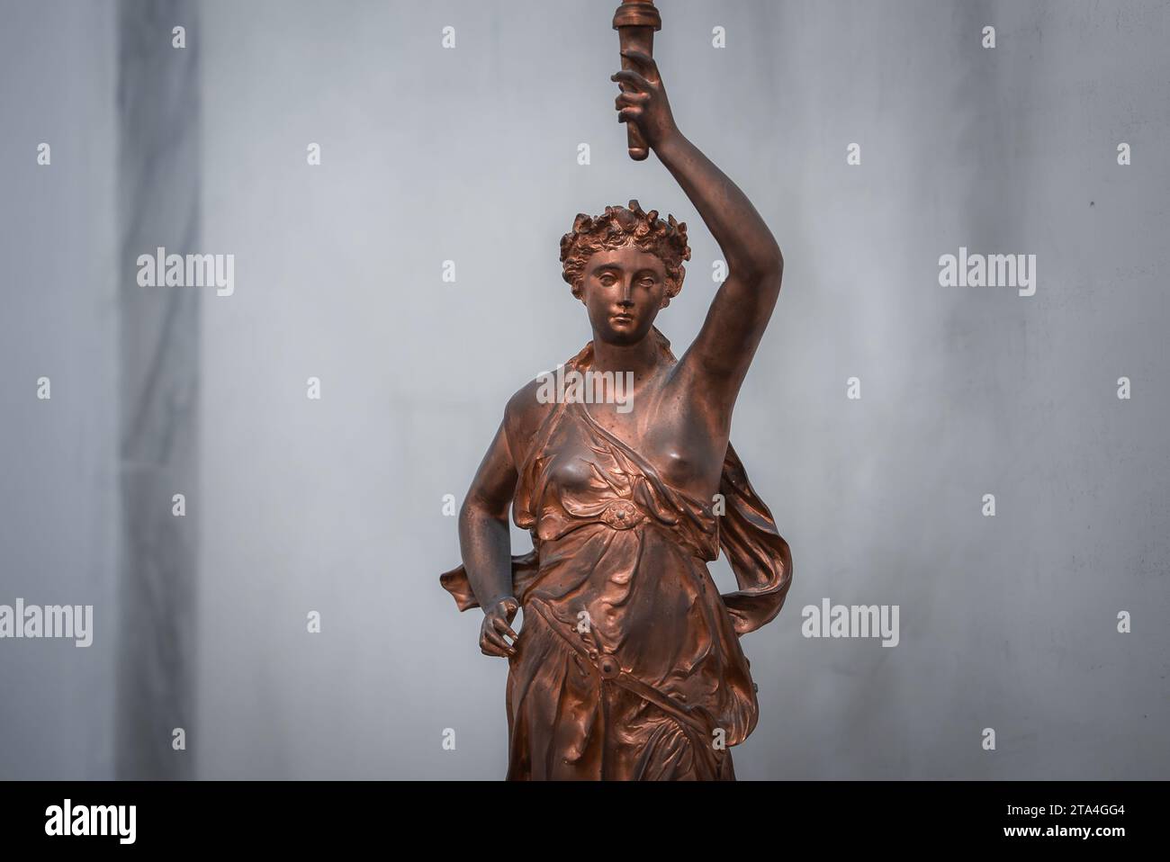 Bronze statue of woman holding torch on pedestal, isolated, no visible ...
