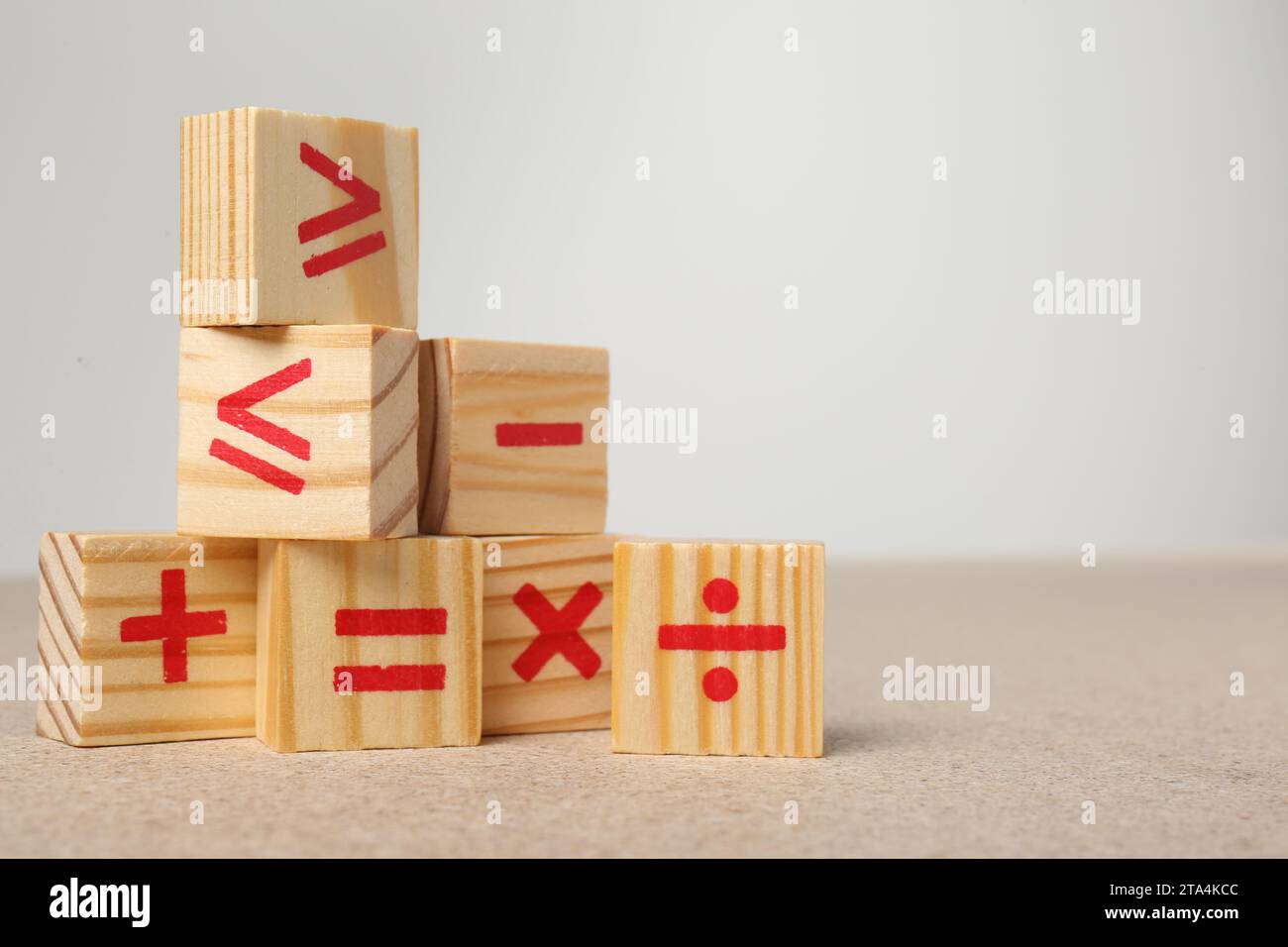 Wooden cubes with mathematical symbols on table against light ...