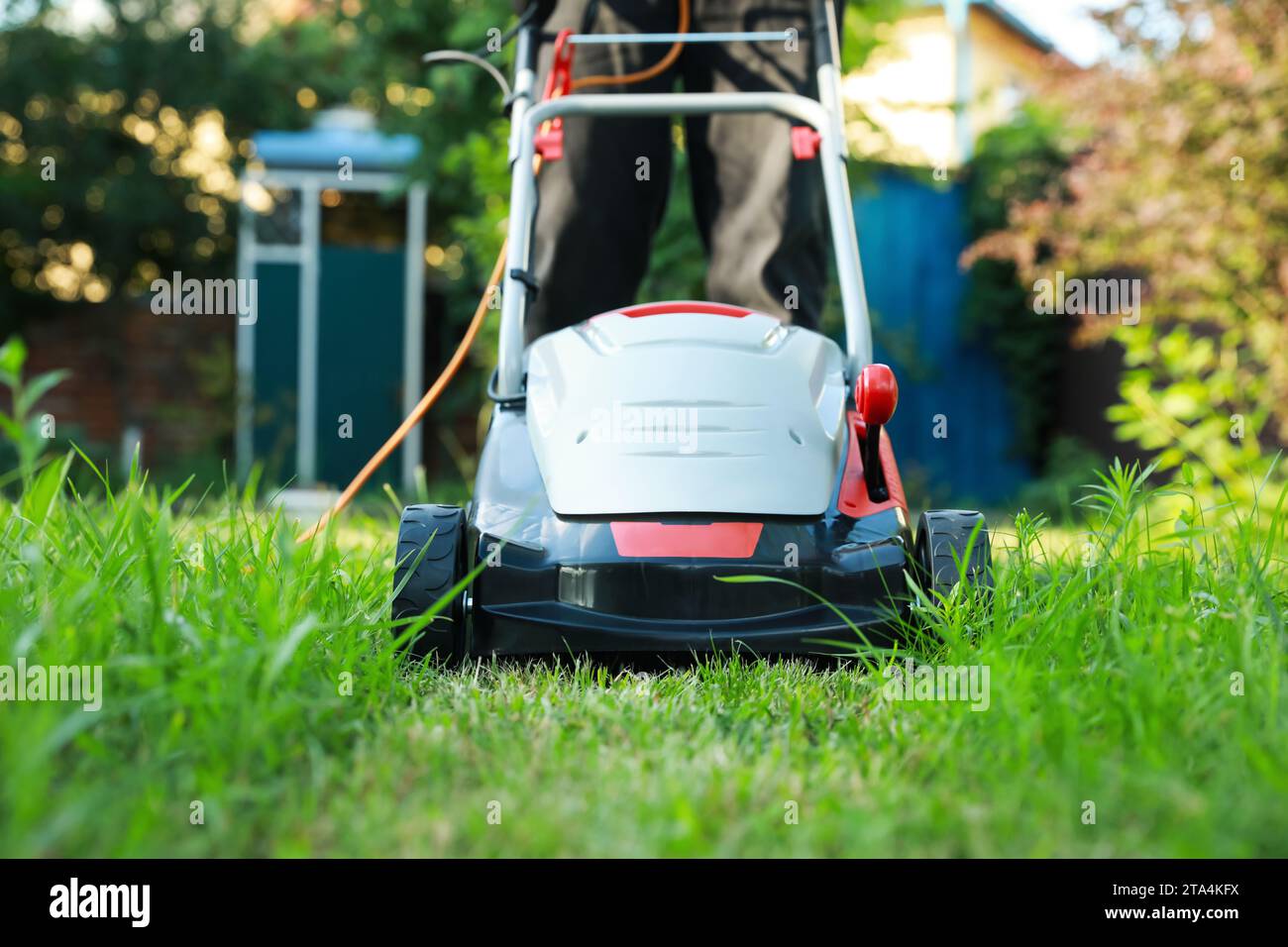 Man cutting grass with lawn mower in garden, closeup Stock Photo - Alamy