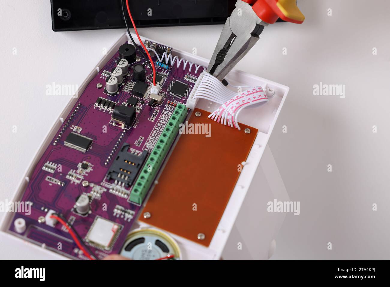 Using pliers while installing alarm system on white wall, closeup Stock ...