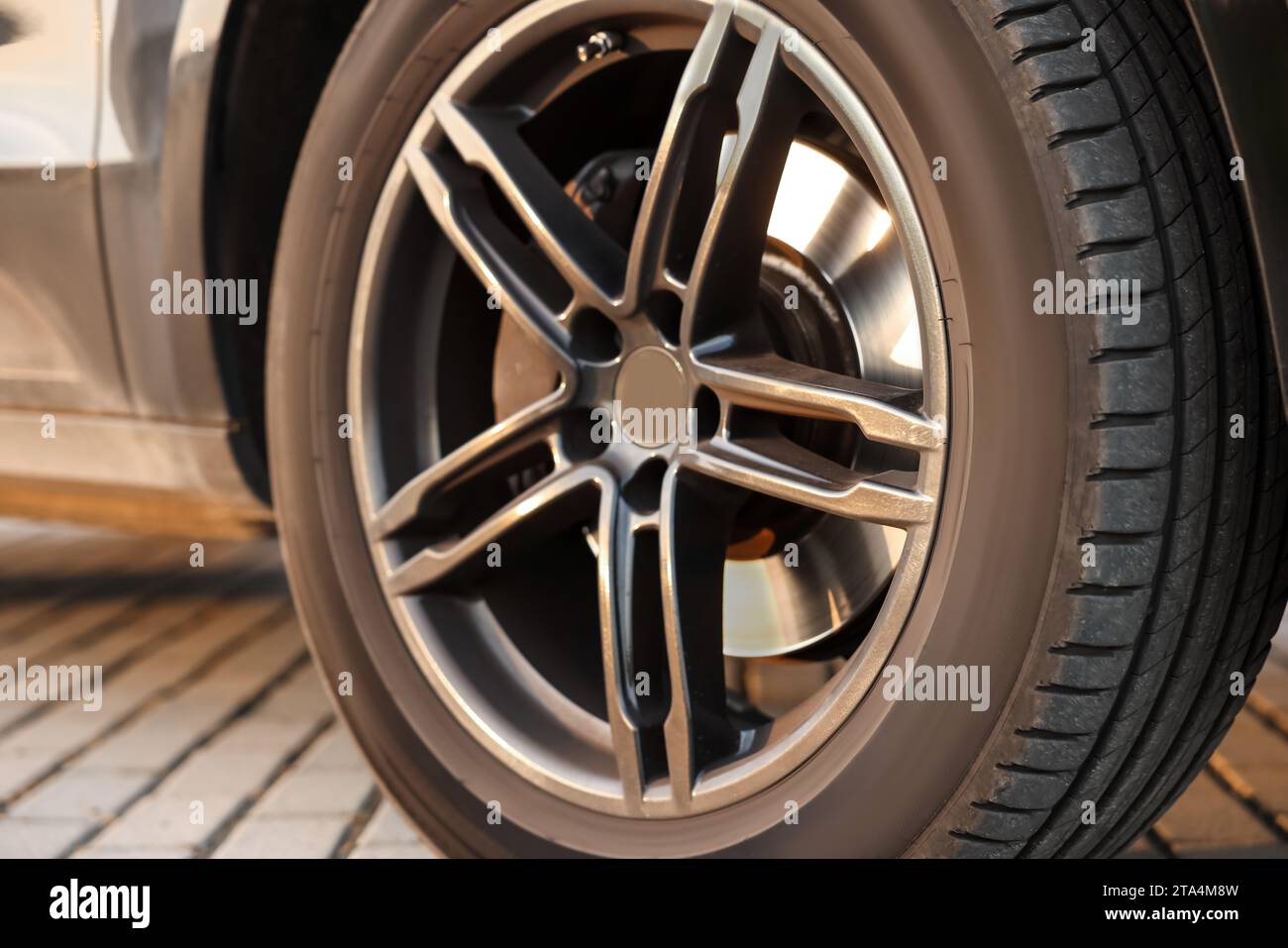 Modern car with big wheel parked on stone pavement outdoors, closeup ...