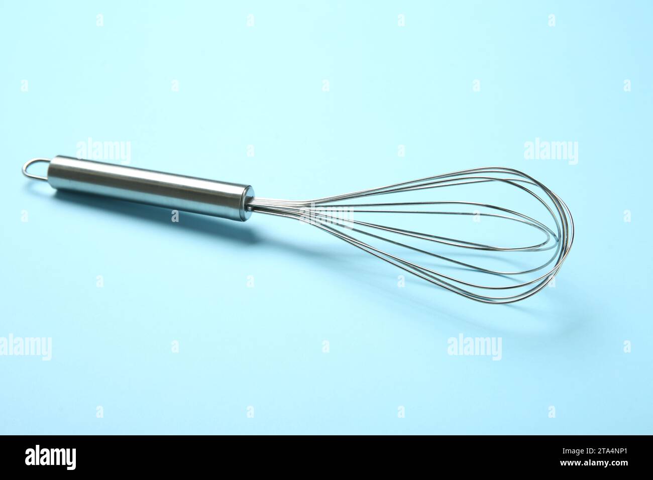 One metal whisk on light blue background Stock Photo - Alamy