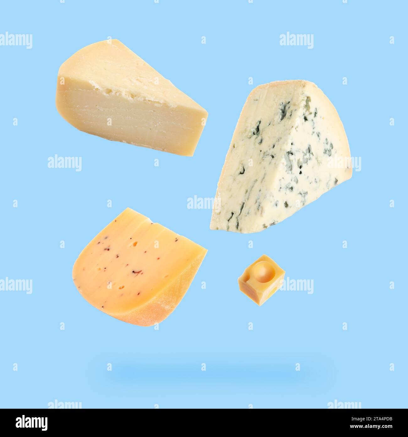 Different kinds of cheese falling on light blue background Stock Photo ...