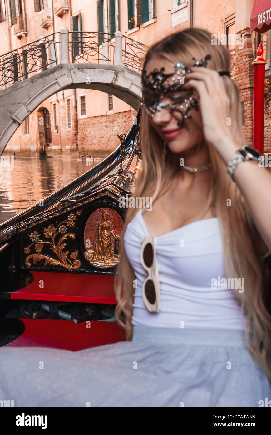 Woman wearing traditional Venetian mask rides gondola through scenic ...