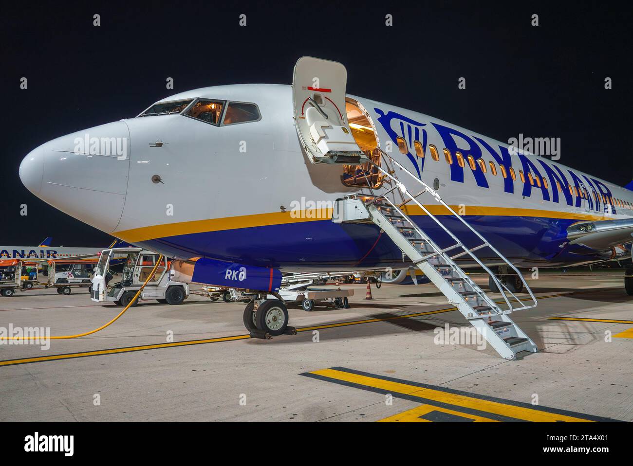 Illuminated Ryanair airplane parked on tarmac at night with dark sky ...