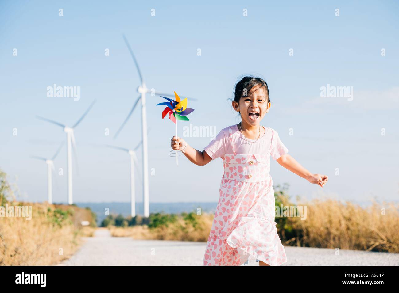 Child's playful exploration by windmills, little girl runs with ...