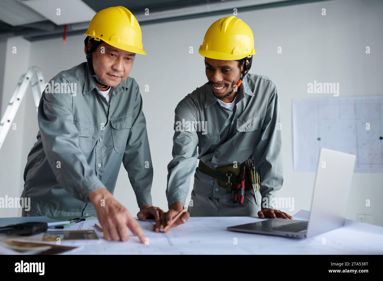 Diverse team of civil engineers discussing details of construction plan ...