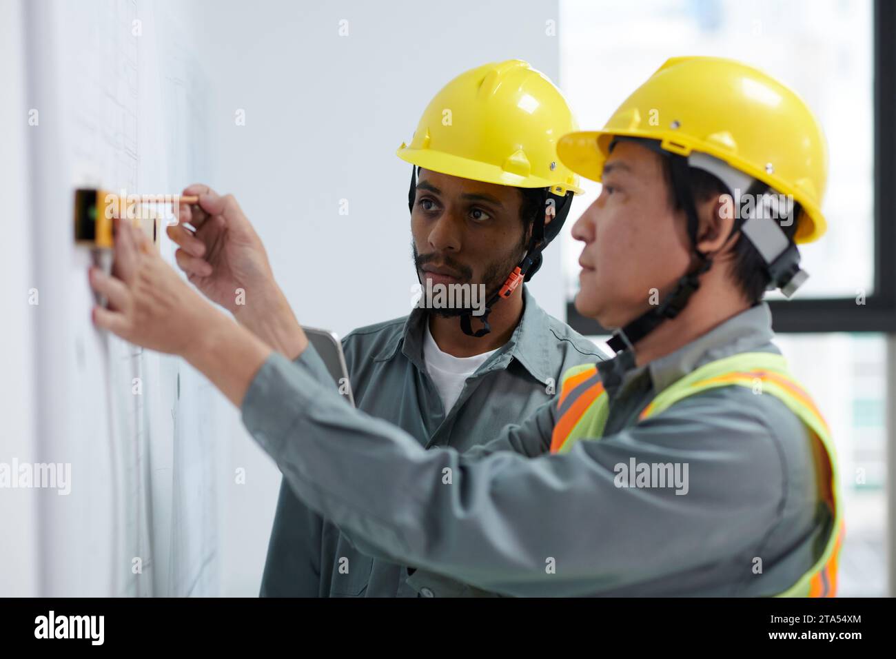 Engineer using construction level when checking evenness of wall on ...